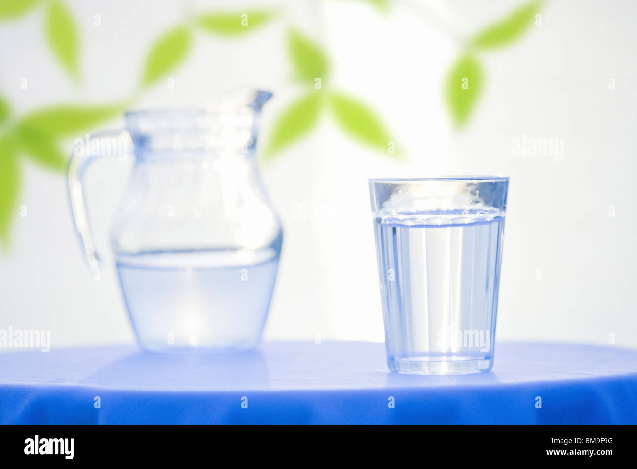 Glass and pitcher with water on table, white background Stock Photo - Alamy