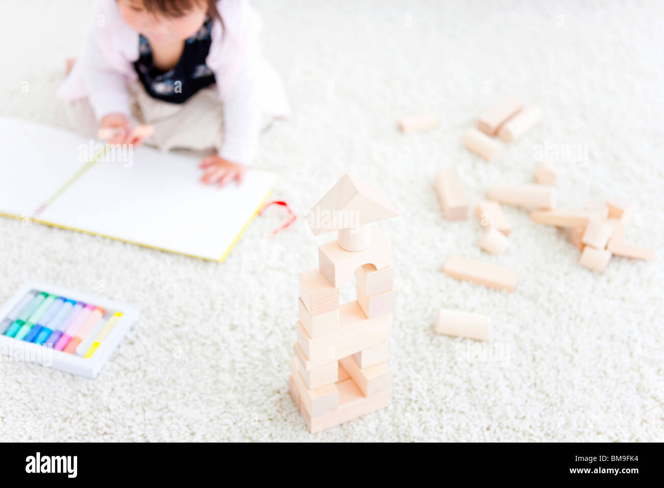 Baby girl drawing next to wooden building blocks Stock Photo - Alamy
