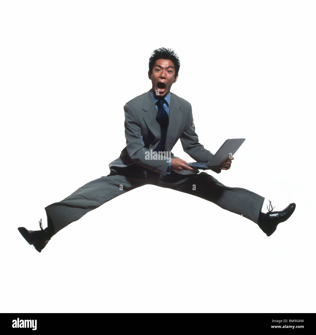 Young businessman jumping with laptop Stock Photo - Alamy