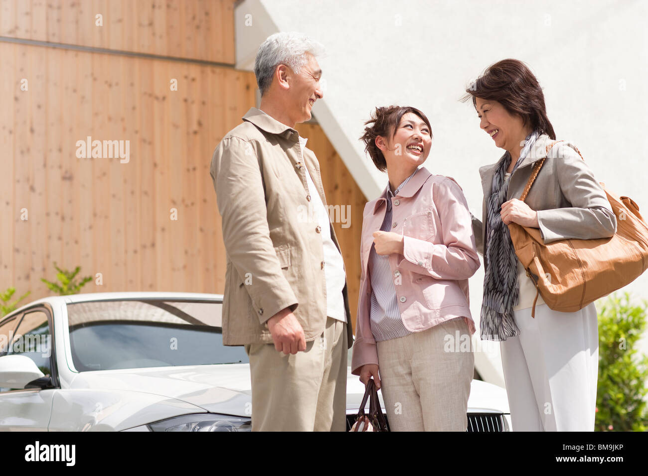 Young woman with parents standing by car, smiling Stock Photo - Alamy