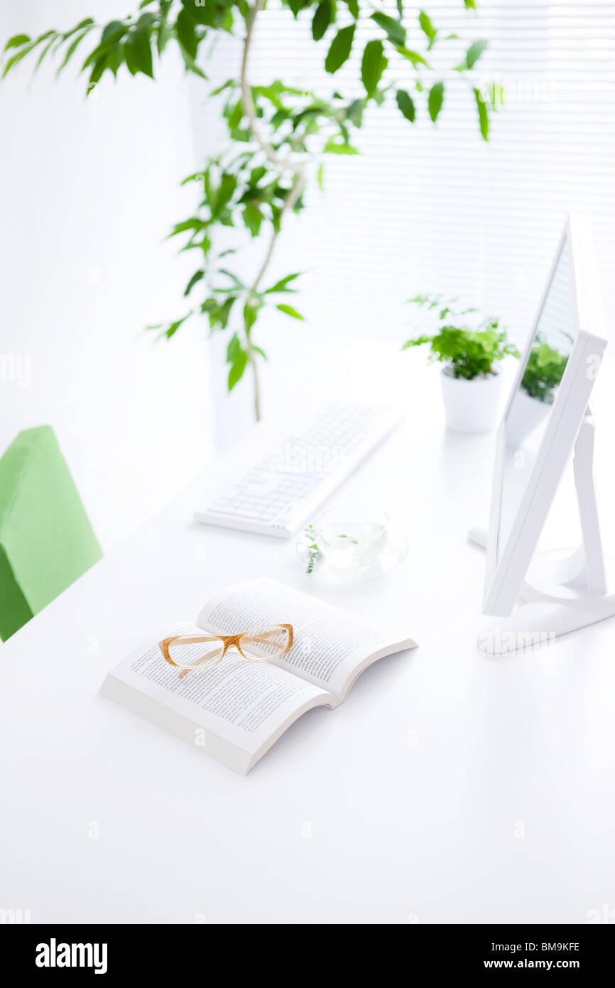 Computer and book on desk in office Stock Photo - Alamy