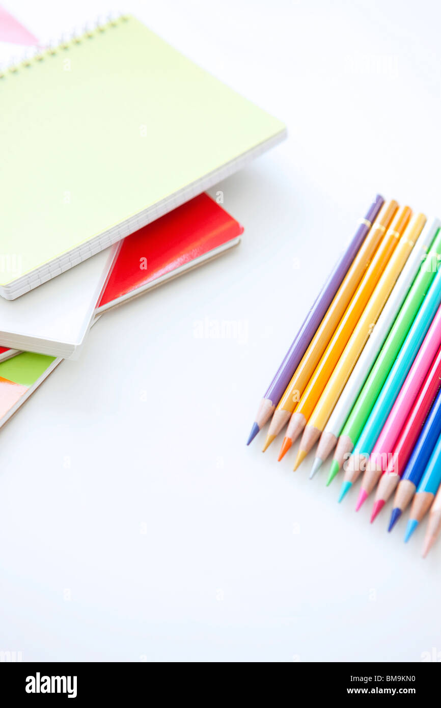 Colored pencils and note pads on white background Stock Photo - Alamy