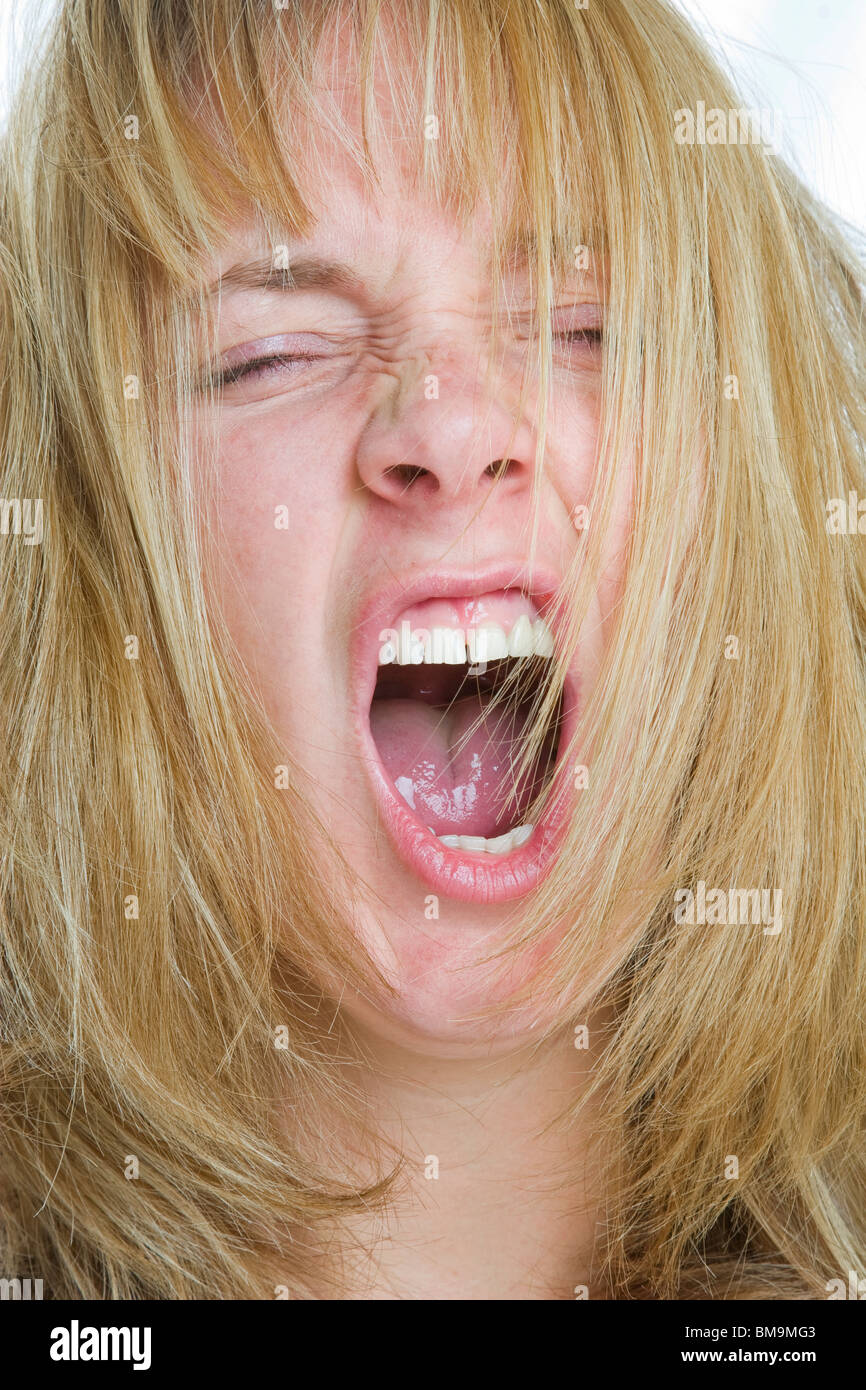 Pretty blond girl giving a big yawn Stock Photo - Alamy