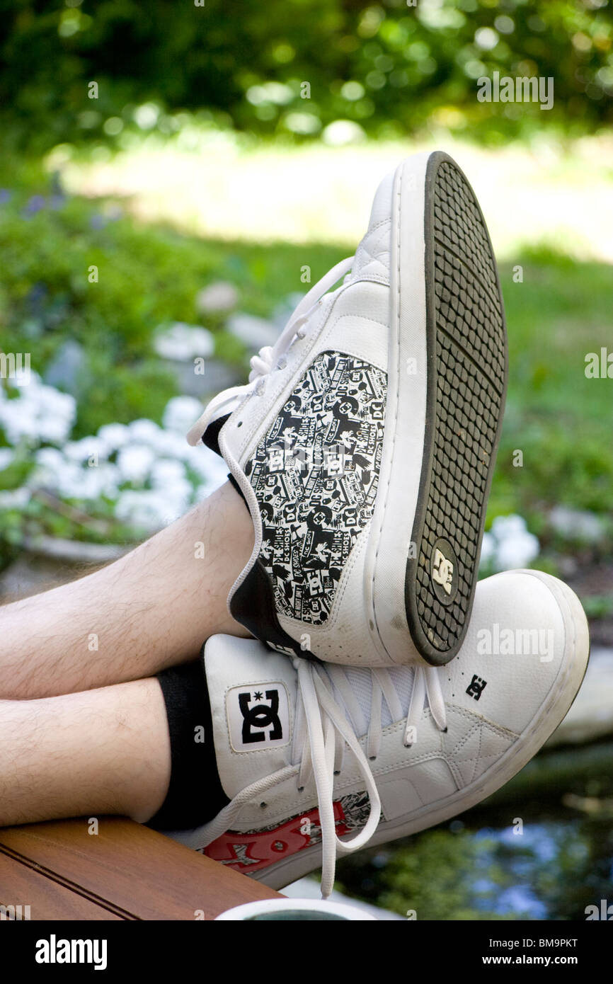 Pair of crossed feet with trainers resting on a table Stock Photo - Alamy