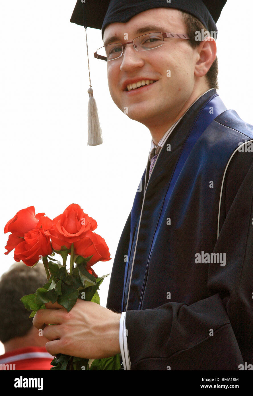 Student holding red roses after his graduation ceremony Stock Photo - Alamy