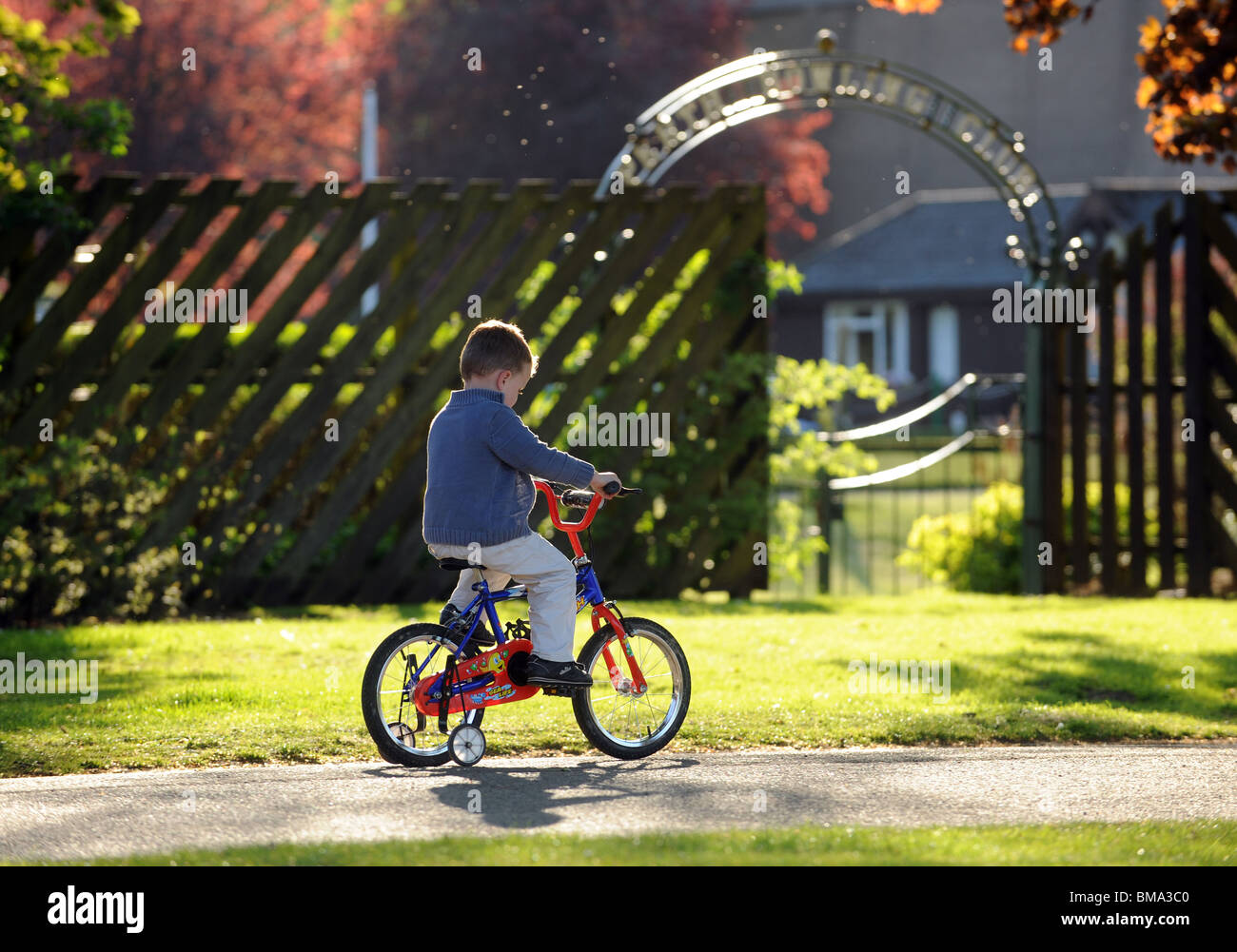 Young boy cycles through the park Stock Photo - Alamy
