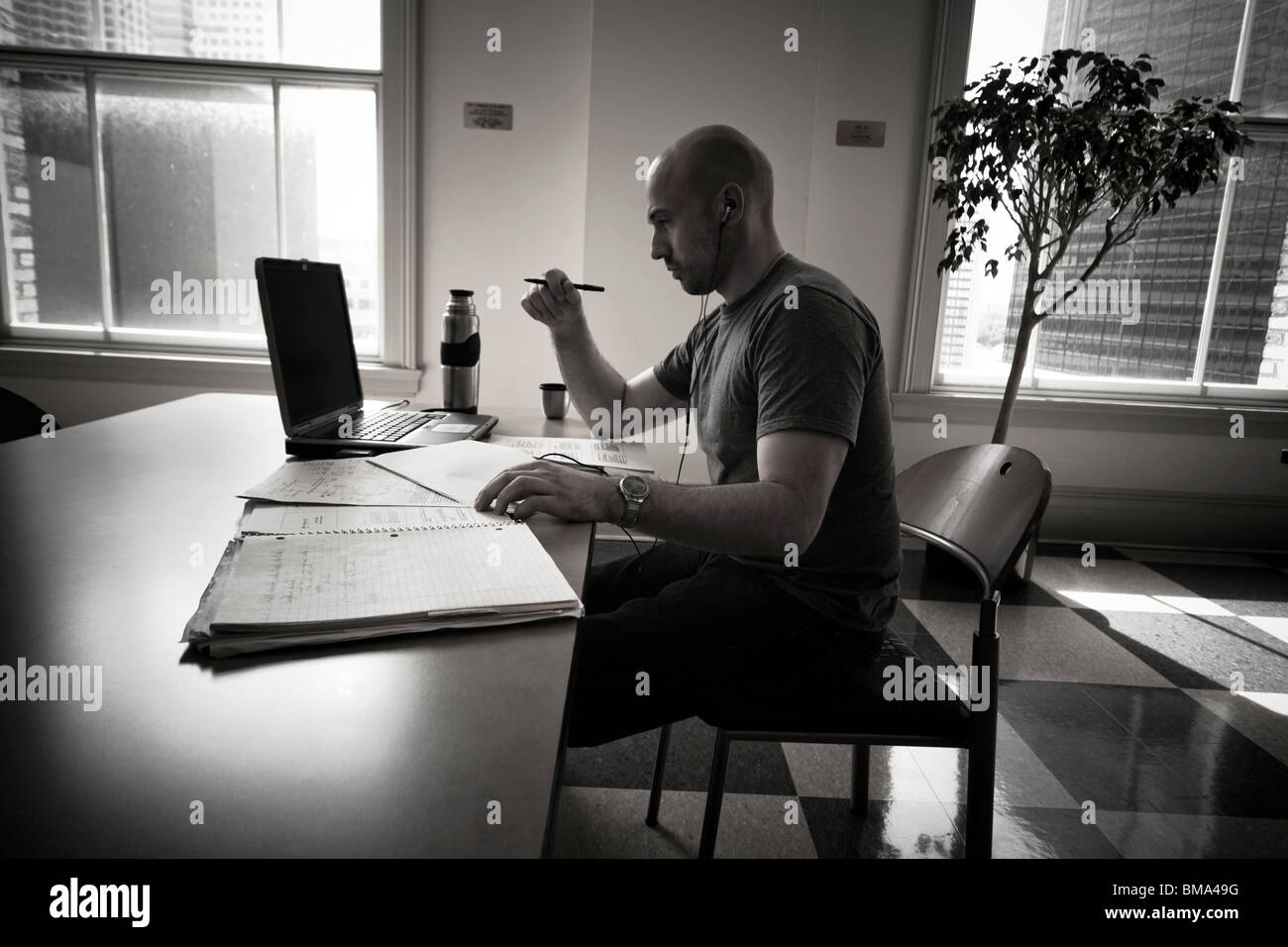 Balding young man working on his laptop computer in the dining area at ...