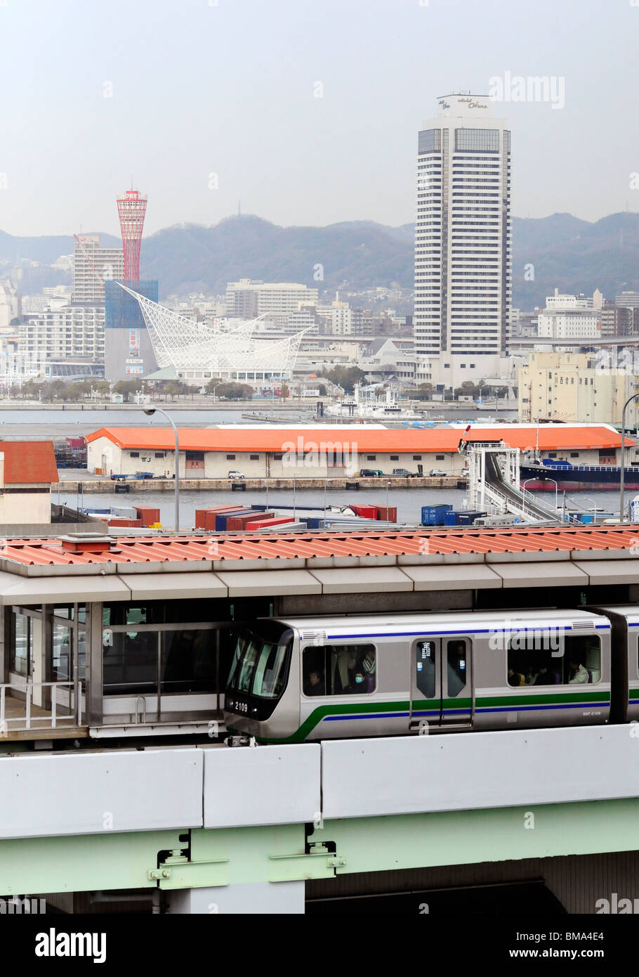 A train on the kobe Metro Rail system with the tower and the maritime ...