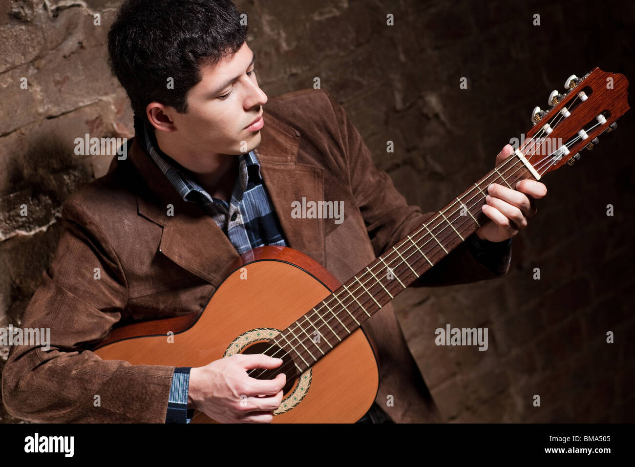 Young man playing on guitar. Camera angle view Stock Photo - Alamy