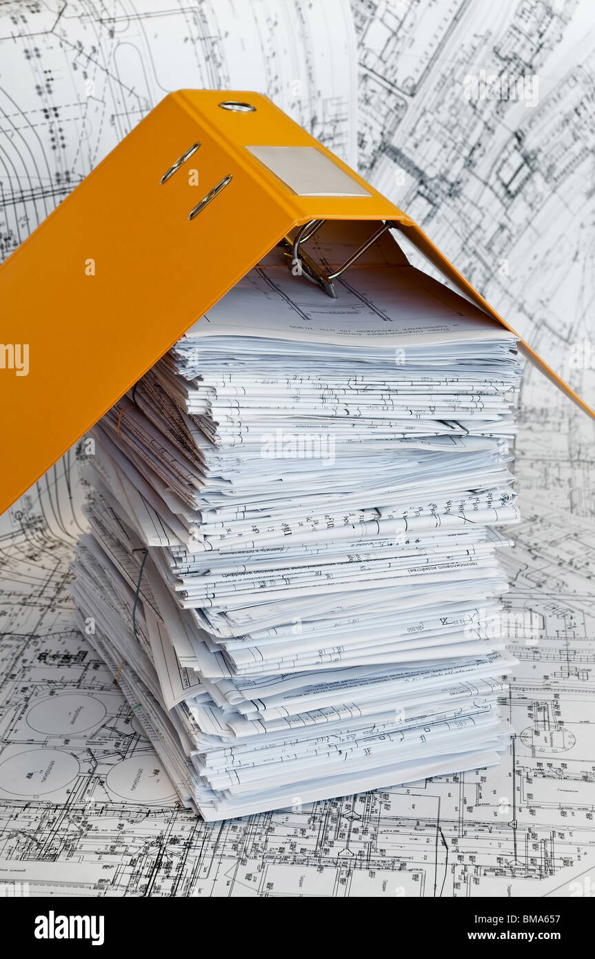 Big heap of design and project drawings under yellow folder on the ...