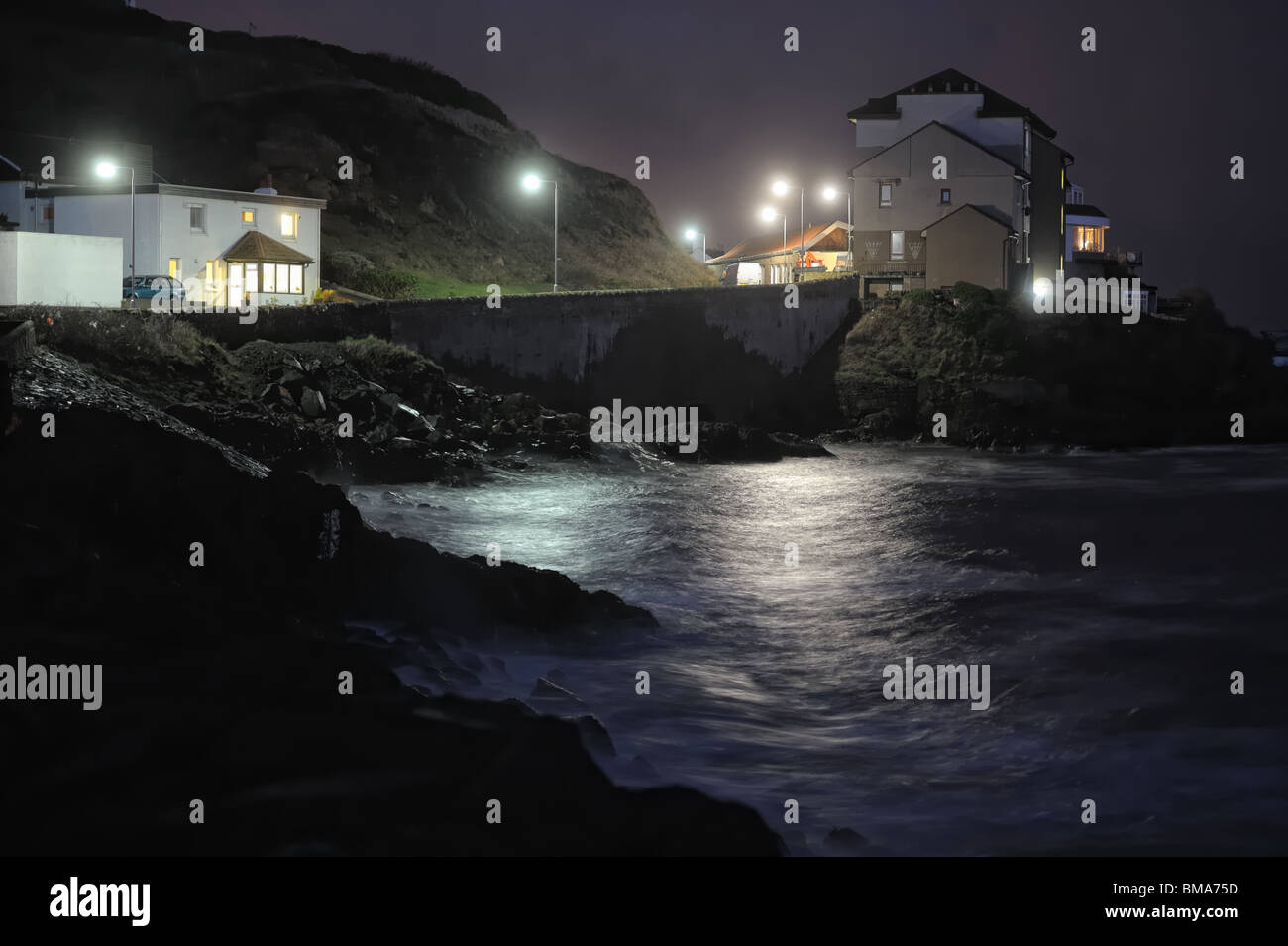 Seafront houses on a rocky coastline at night Stock Photo - Alamy