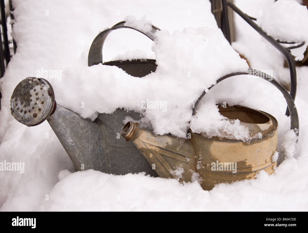 Two watering cans in the snow Stock Photo - Alamy