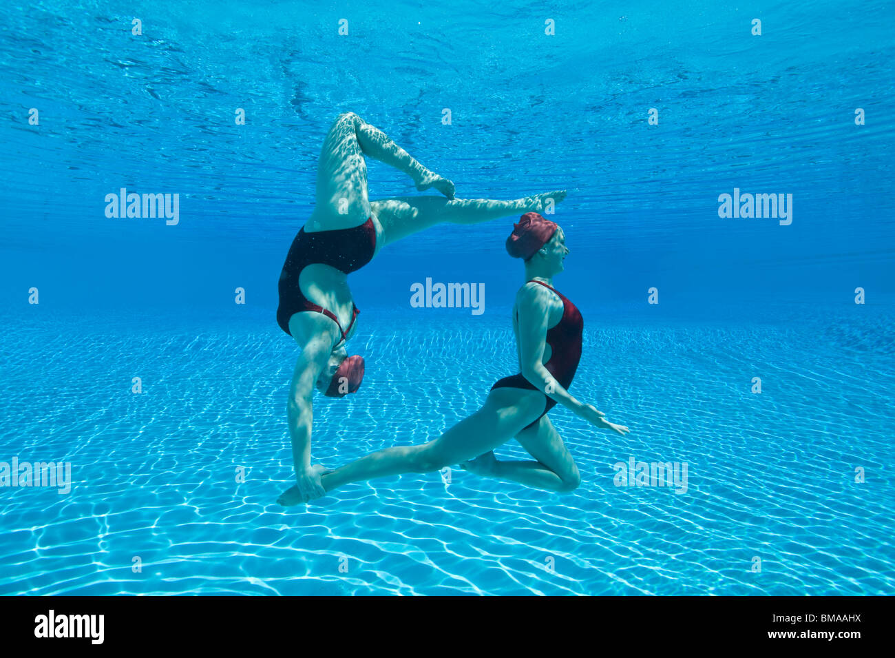 Synchronised swimmers balance underwater Stock Photo - Alamy