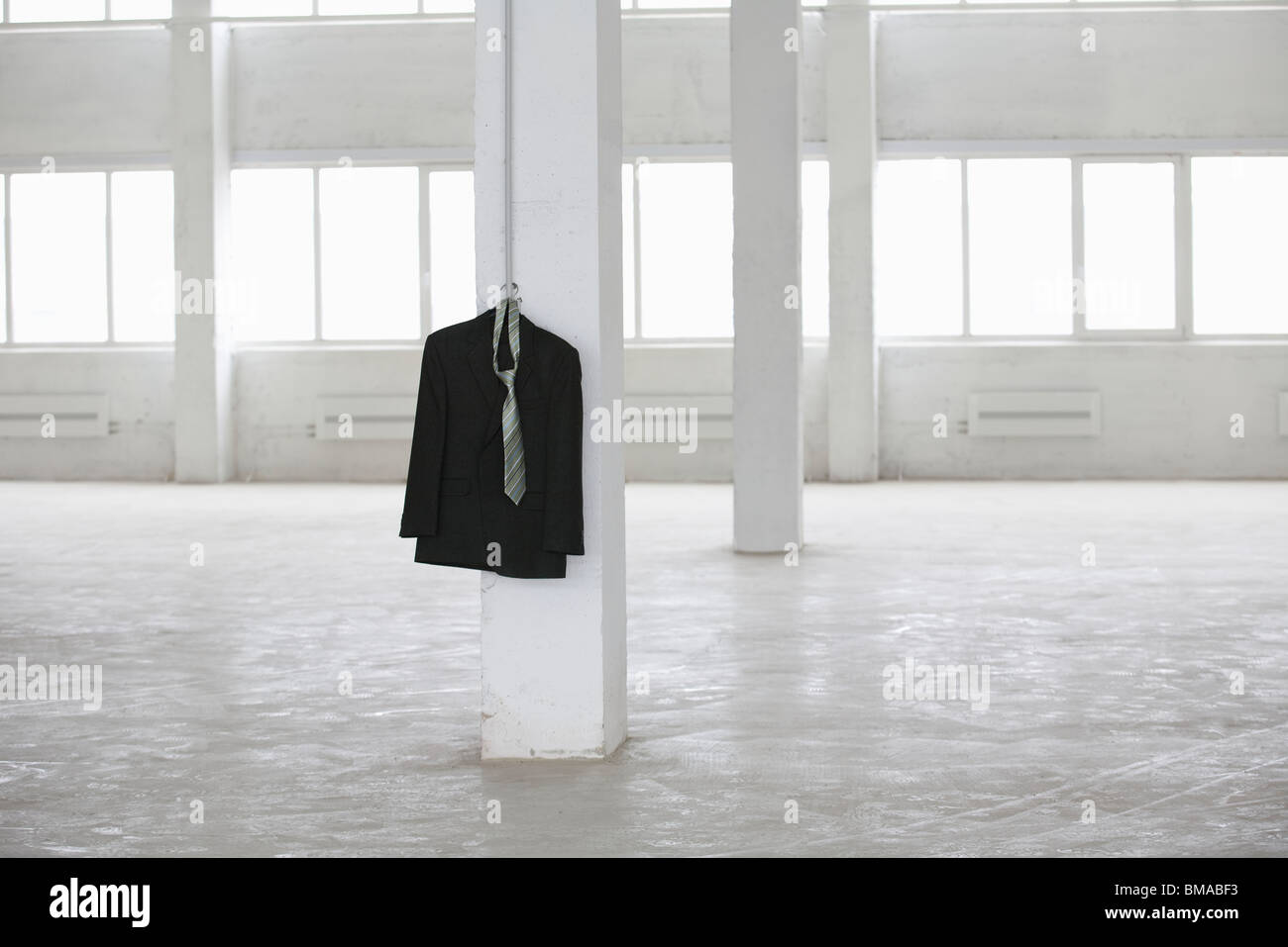 Suit jacket hangs on pillar in empty warehouse Stock Photo - Alamy