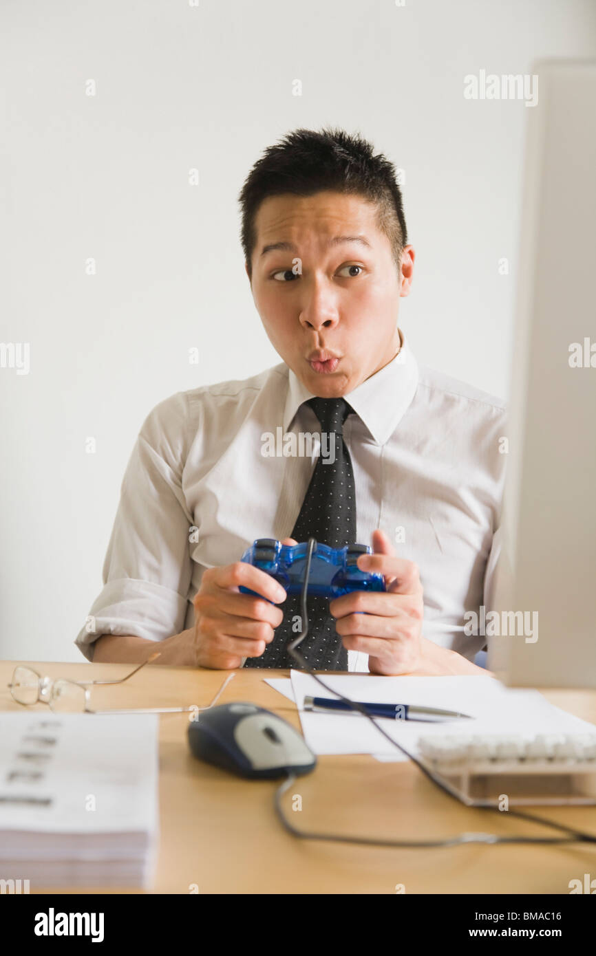 Businessman Playing Video Game at Desk Stock Photo - Alamy