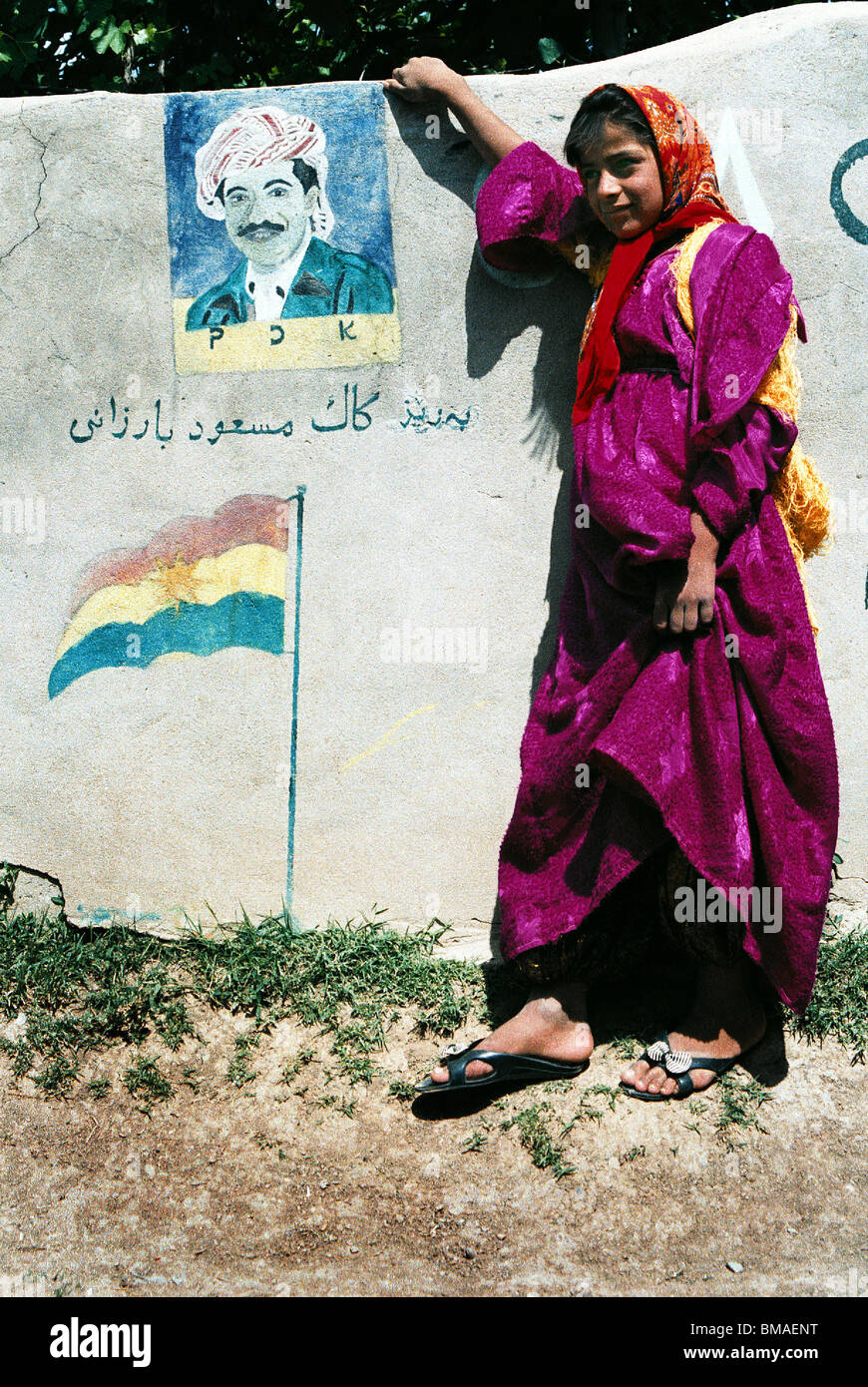 April 1992. Dahok, Northern Iraq. A Kurdish girl stands by a mural ...