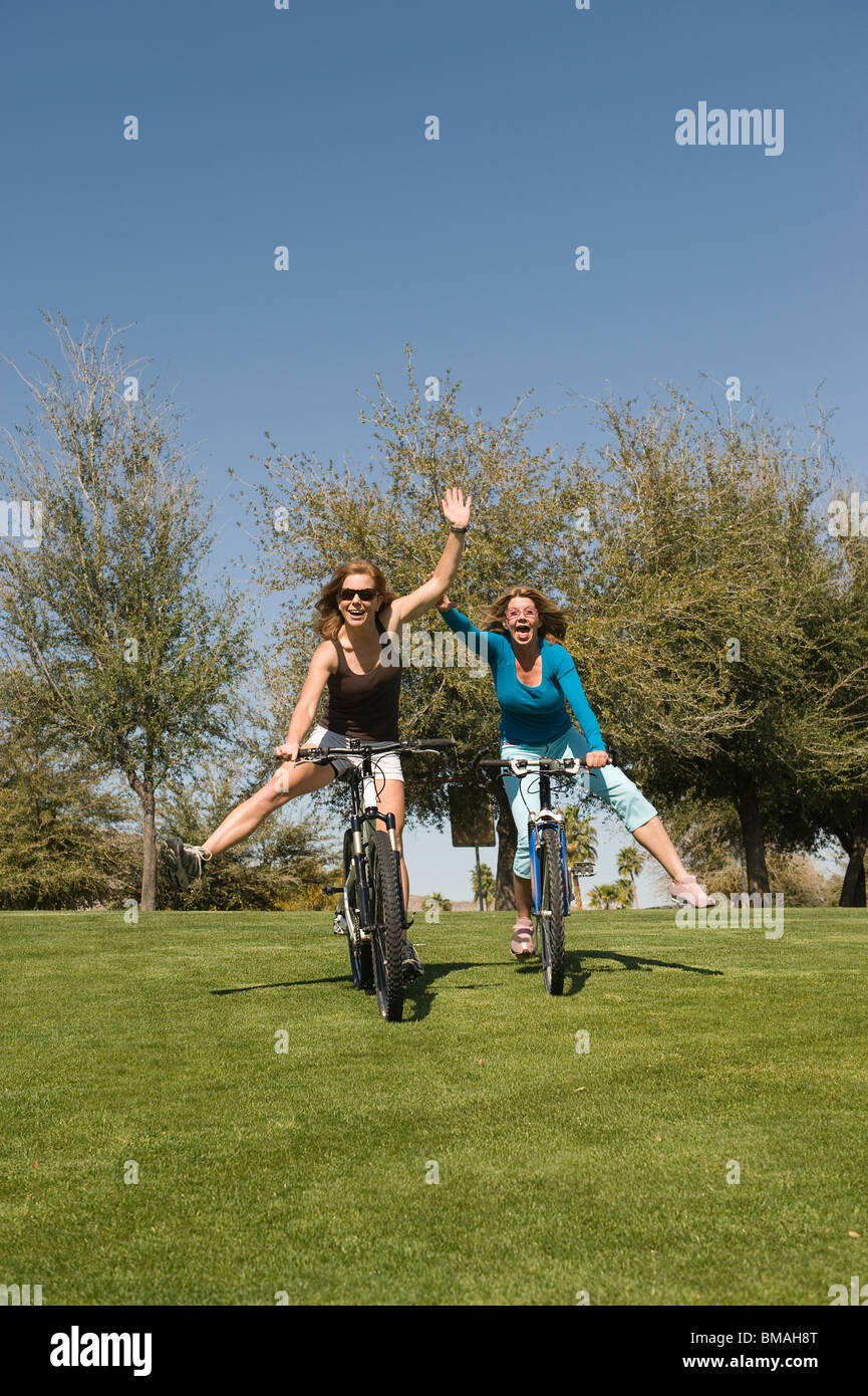 Two friends cycle downhill one-handed Stock Photo - Alamy