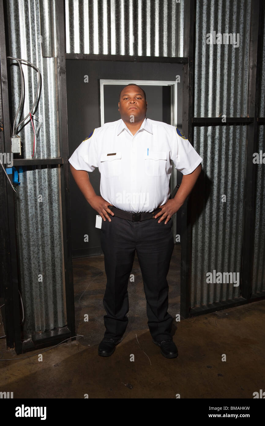 Security guard stands at corrugated metal doorway Stock Photo - Alamy