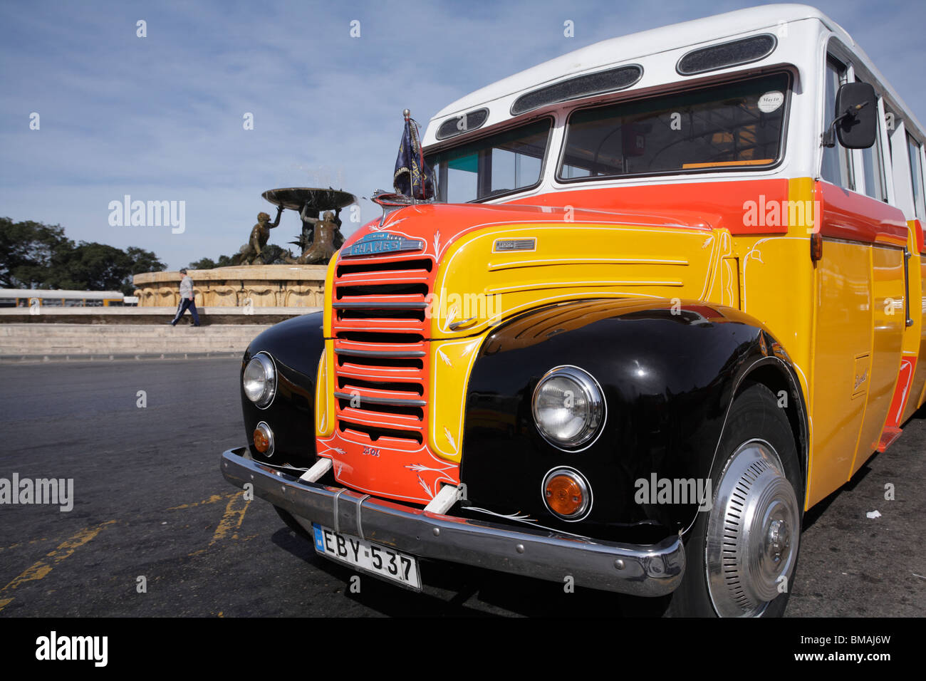 An old fashioned 'bull-nose' bus brightly painted yellow red & white ...
