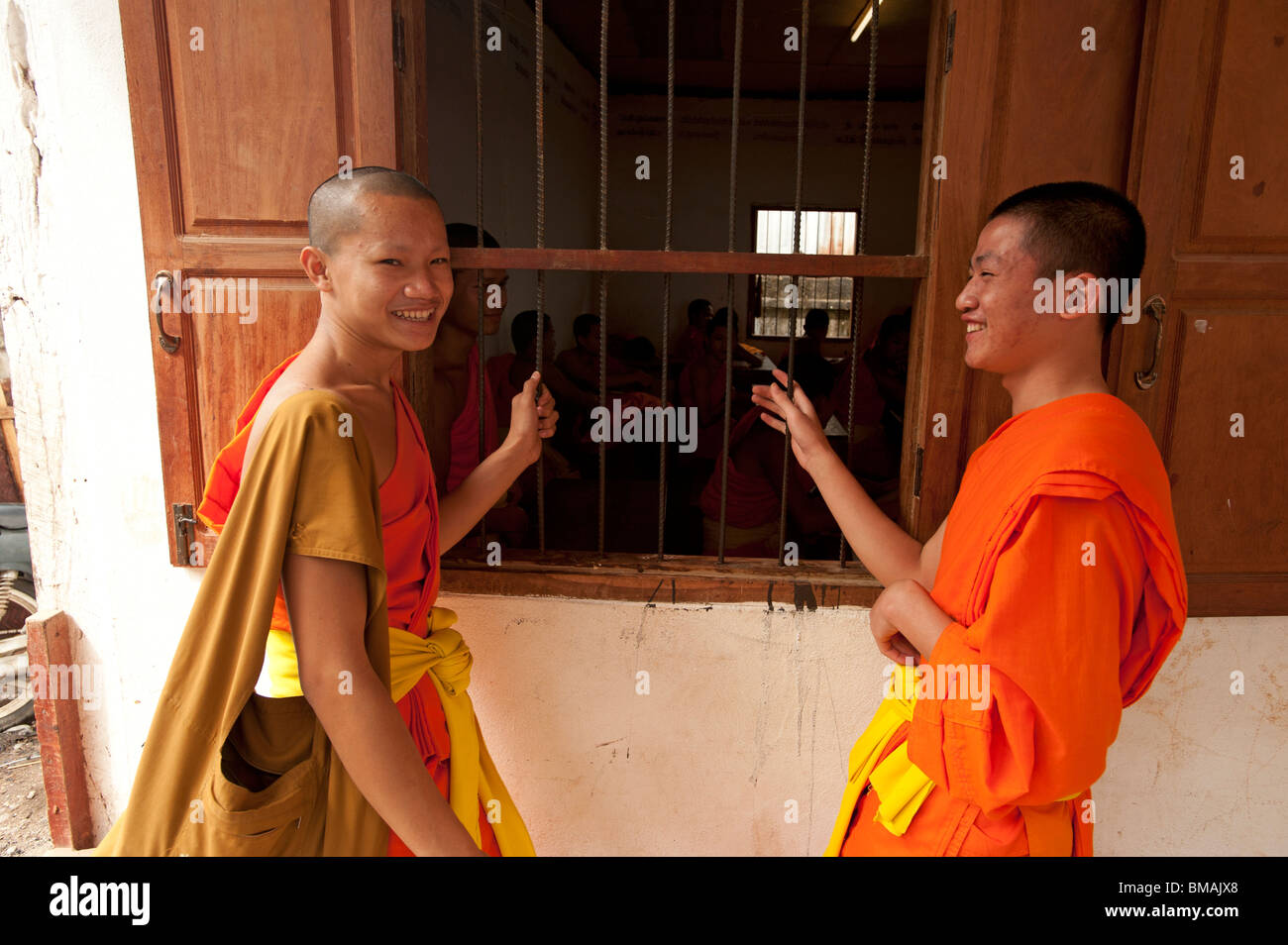 Two happy Buddhist monks at the window of their school room in Luang ...
