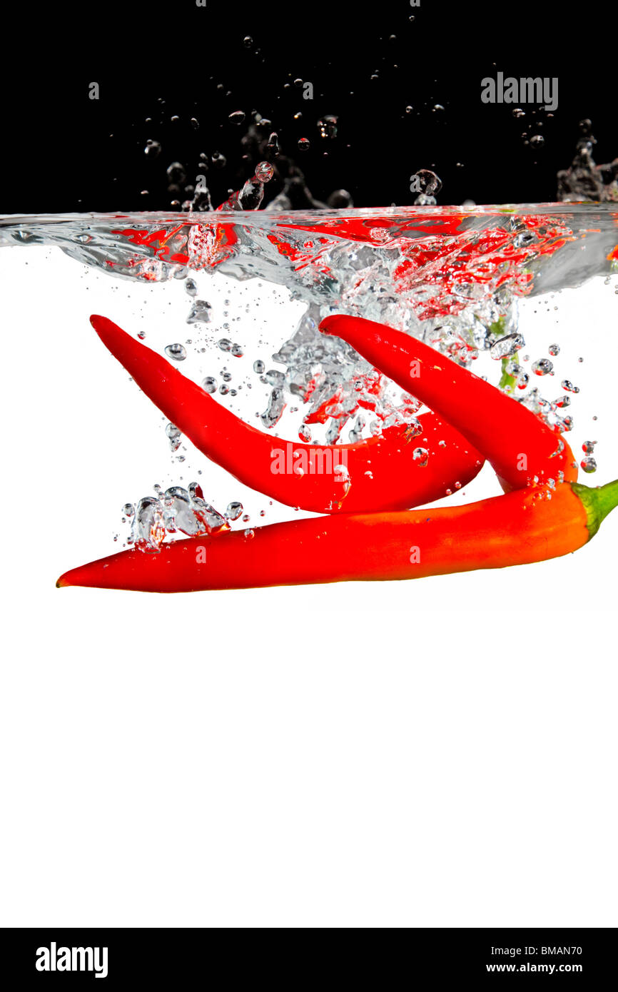 three red chillies thrown in water with black and white background ...