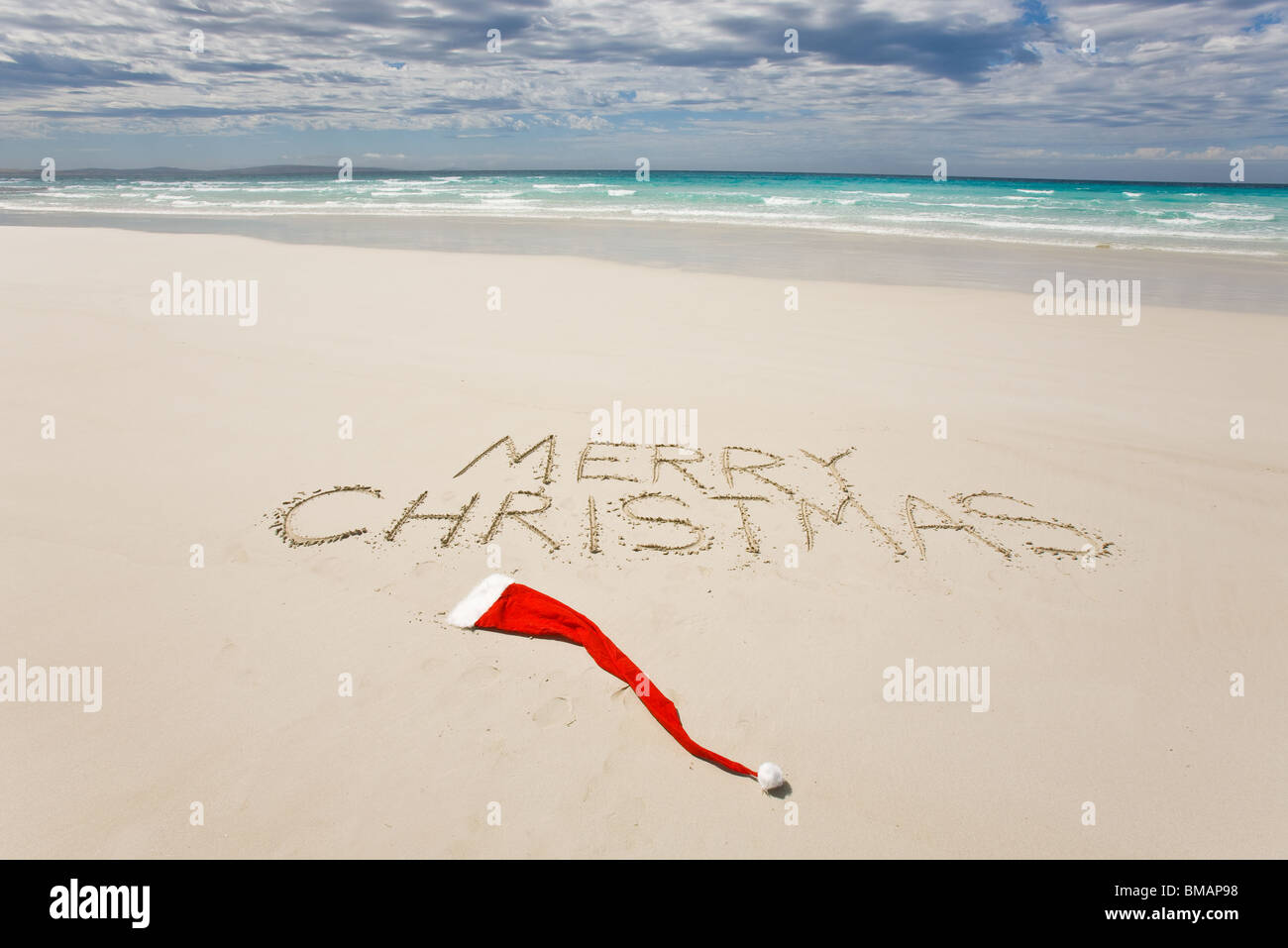 Merry Christmas written on a tropical beach with a santa hat on the ...