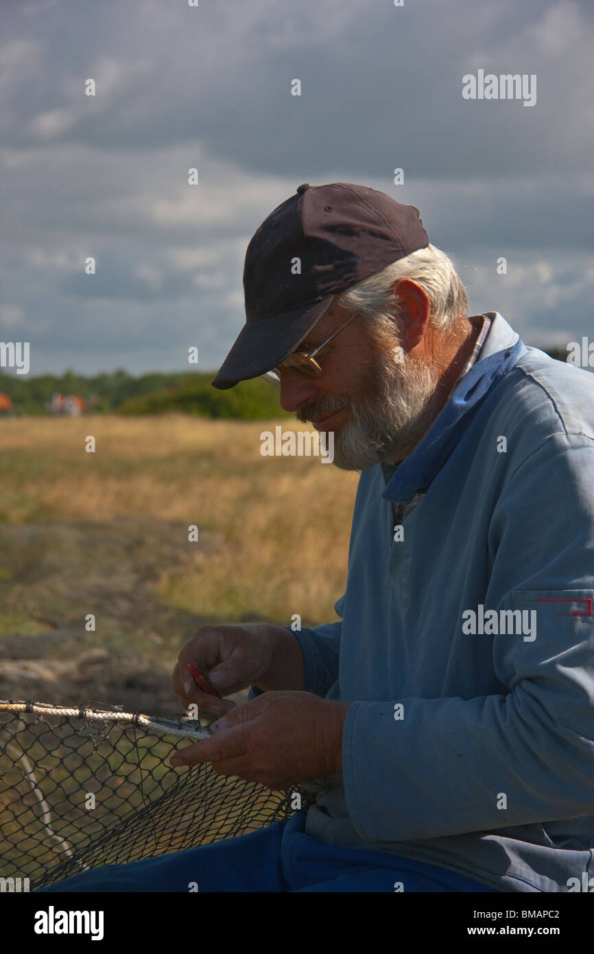 Helnaes Denmark Fisherman repairs nets with a contented smile on his ...