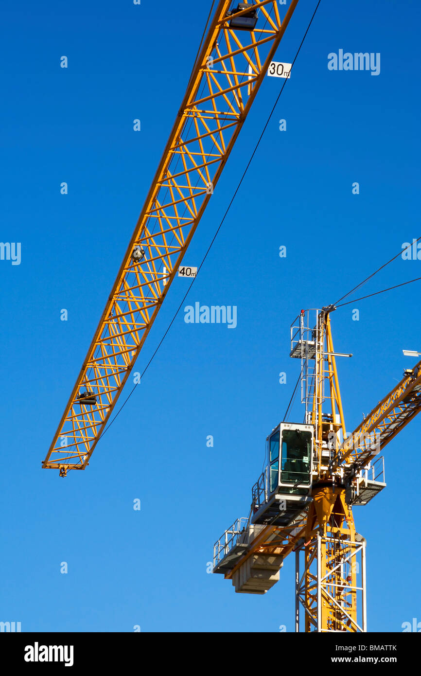 Two construction cranes against a blue sky Stock Photo - Alamy