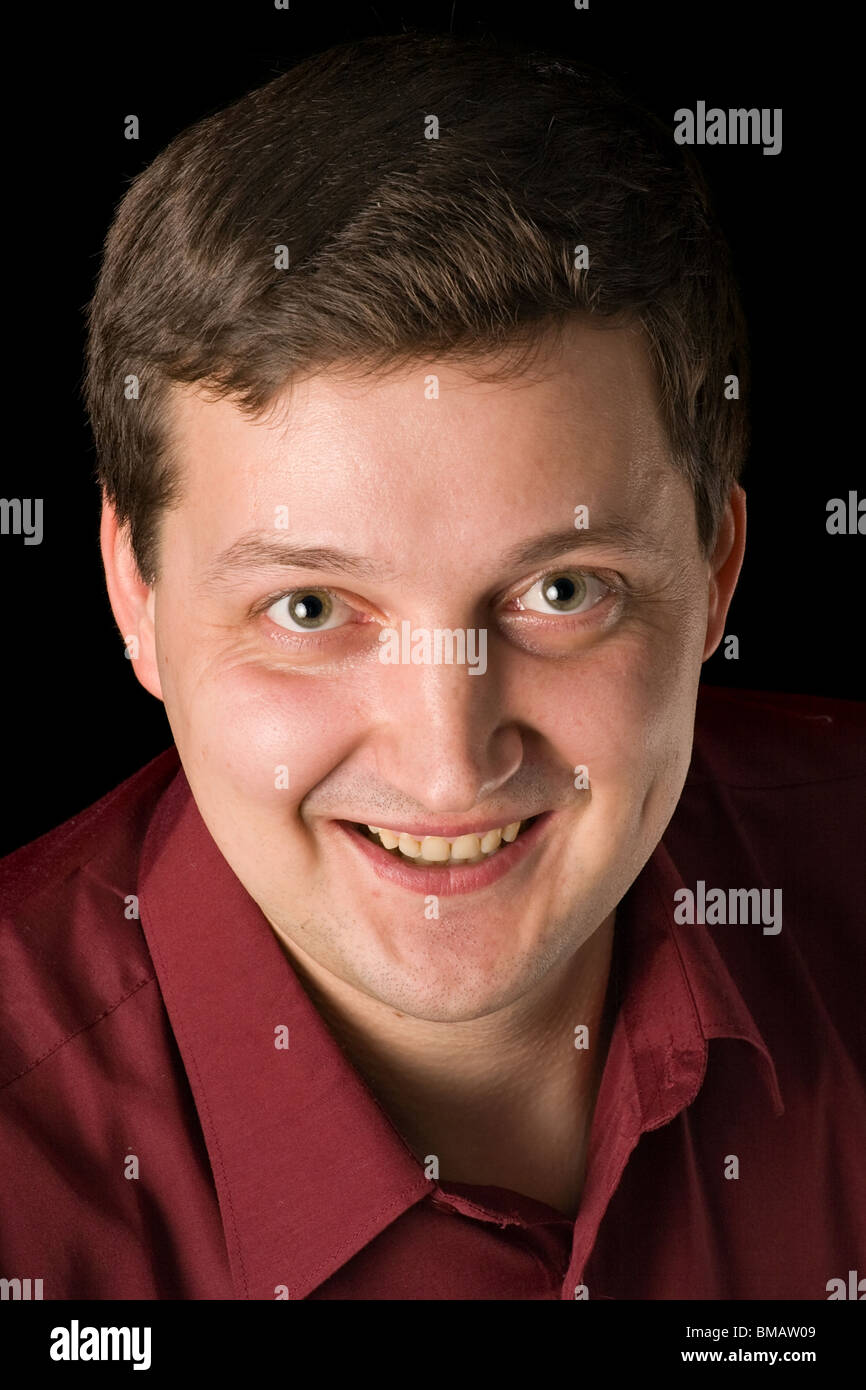 smiling green-eyed man in a red shirt on black background Stock Photo ...