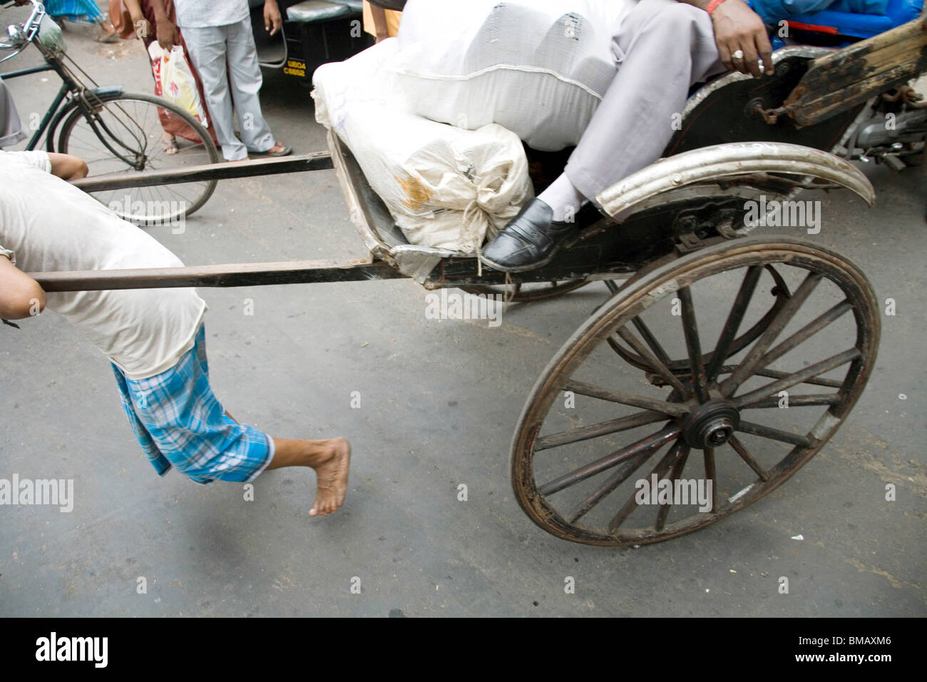 Man pulling hand rickshaw with passenger and luggage ; Calcutta now ...