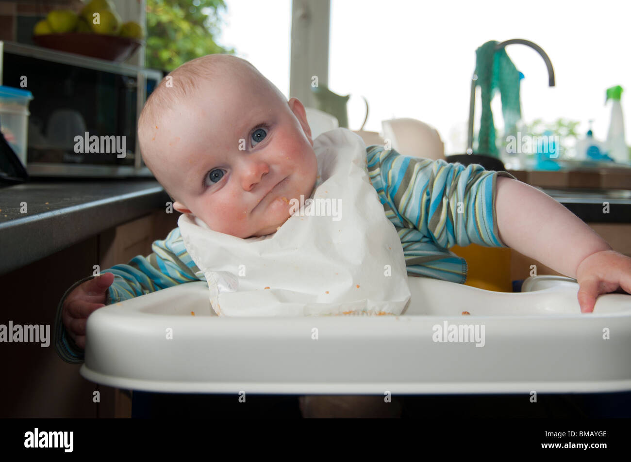 Baby sitting in high chair in kitchen Stock Photo - Alamy