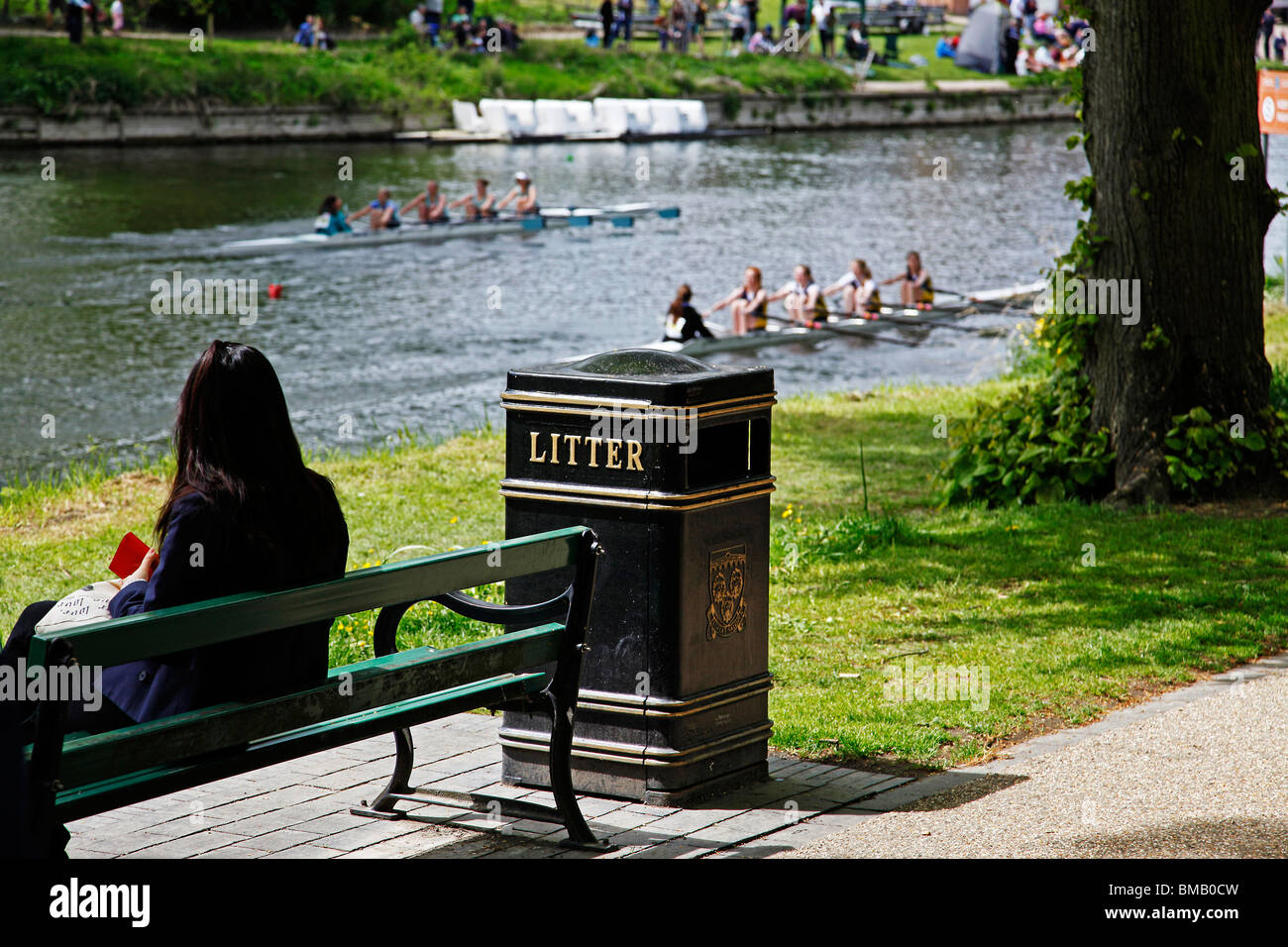 A woman sitting and watching a rowing race on the river Severn Stock ...
