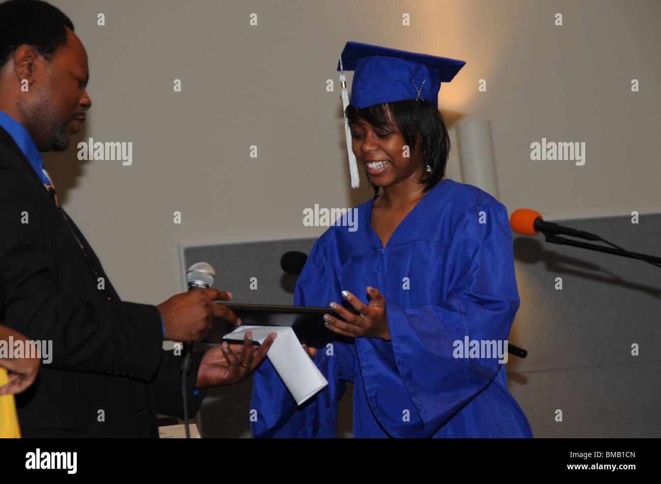 A home schooled high school graduate receives a diploma from her father ...