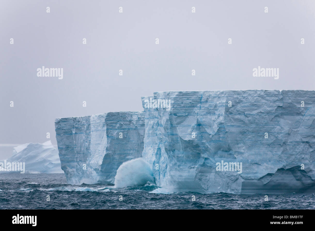 Big ocean wave crashing against giant tall blue icebergs eroding the ...
