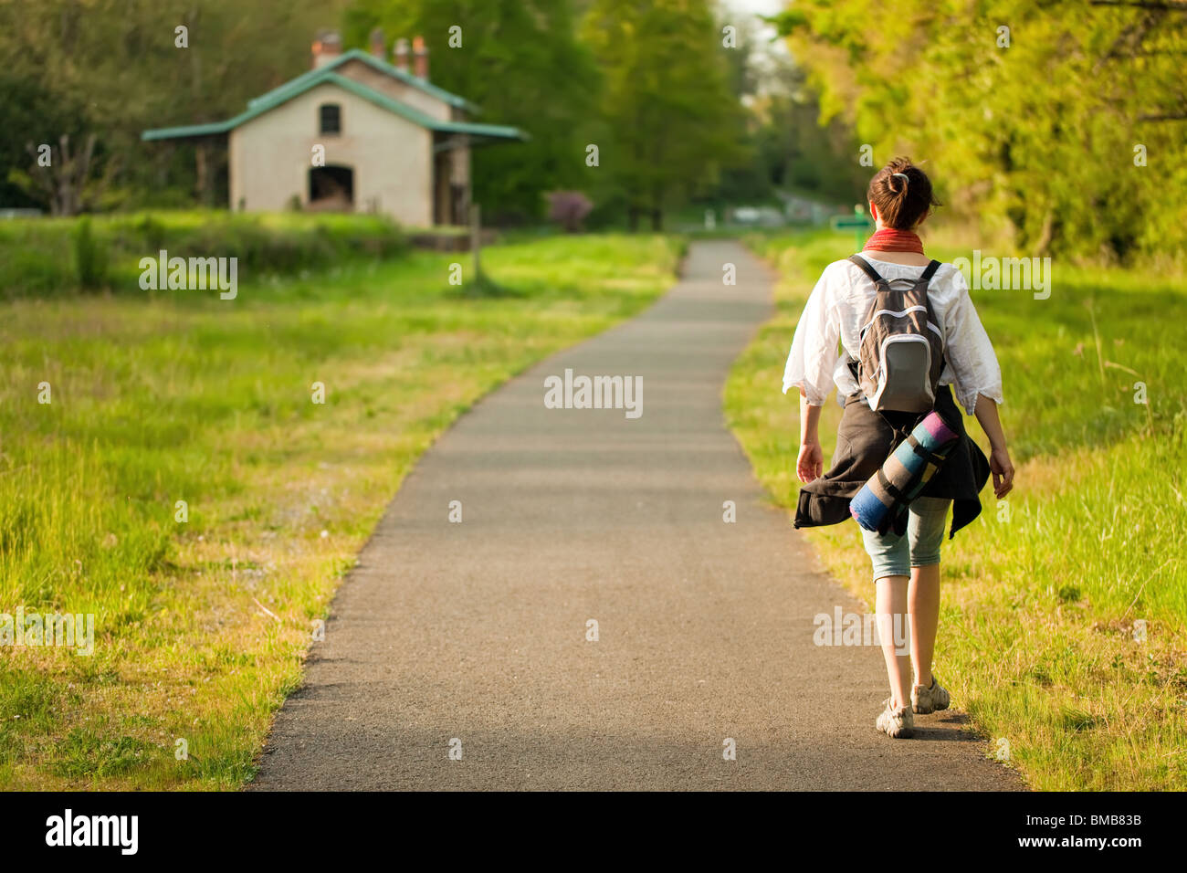 back view of woman walking on country road at springtime in France ...