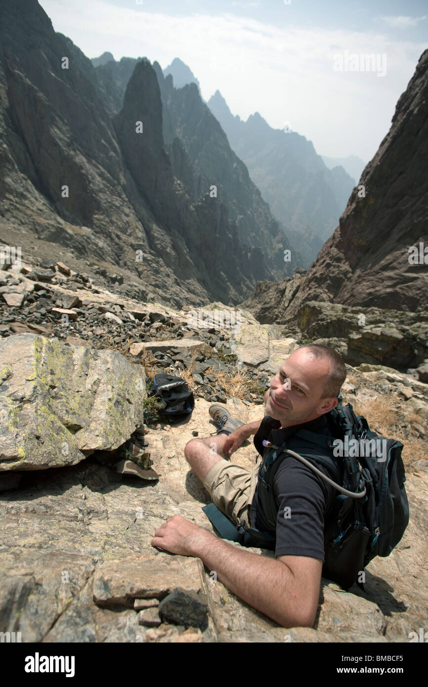 Hiker taking a break in the steep corrie of the Cirque de la Solitude ...