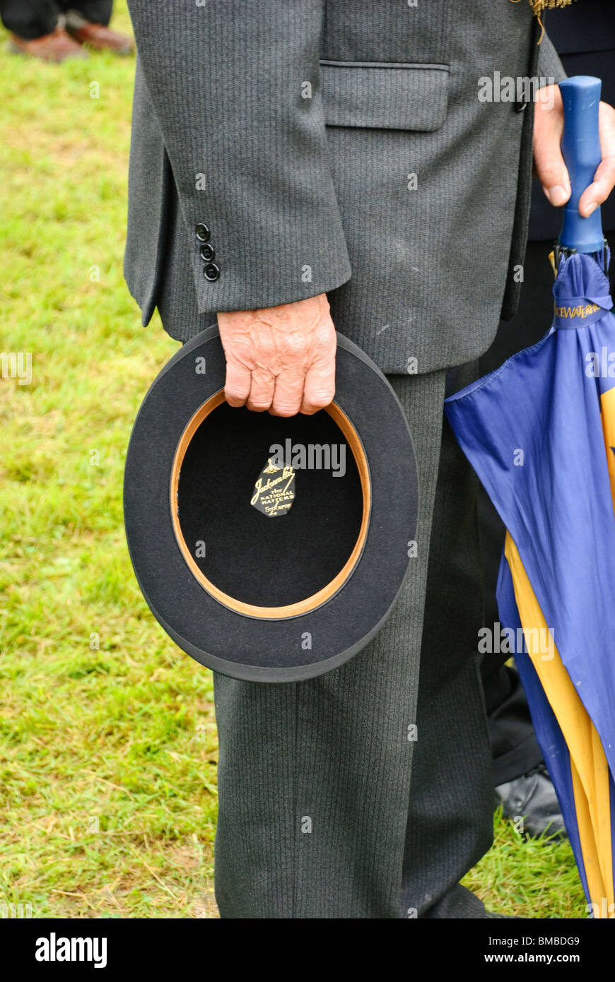 Man in a suit holds a bowler hat by his side Stock Photo - Alamy