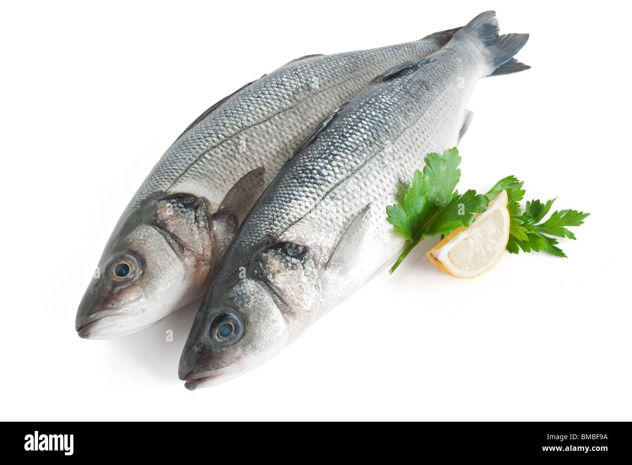 two sea bass with lemon and parsley isolated on white background with ...