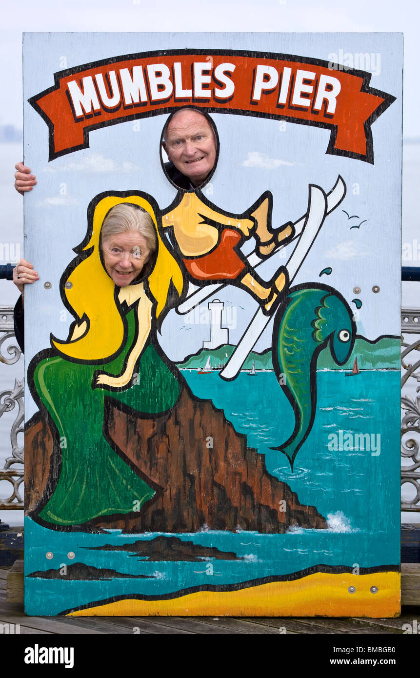 Two Elderly people posing through Pier Sign Mumbles Swansea Stock Photo ...