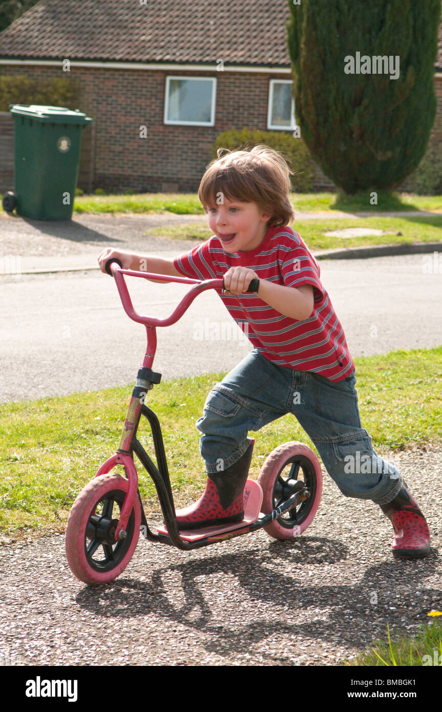young boy riding a toy scooter near road Stock Photo - Alamy