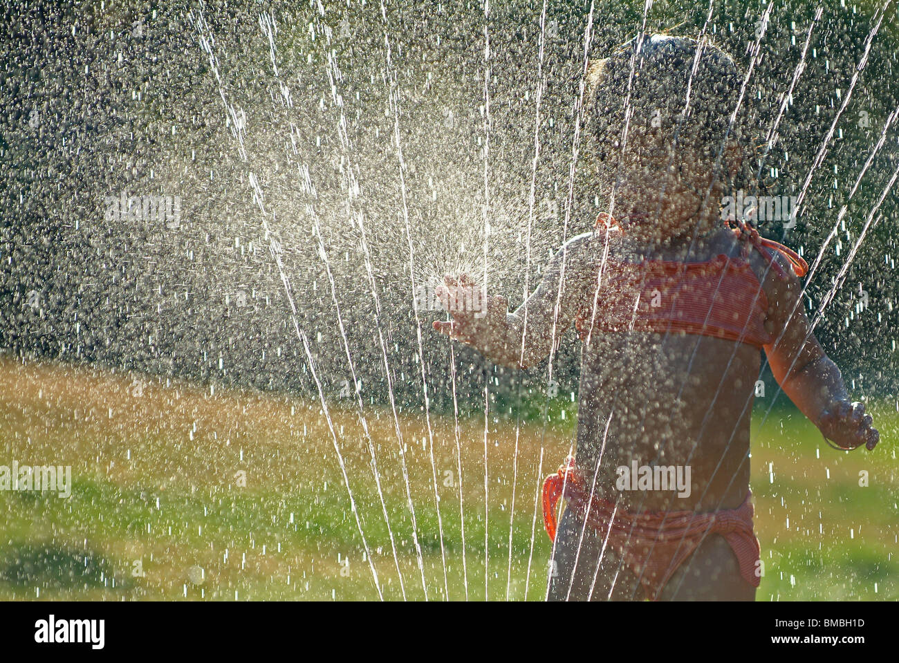 Girl playing in sprinkler Stock Photo - Alamy