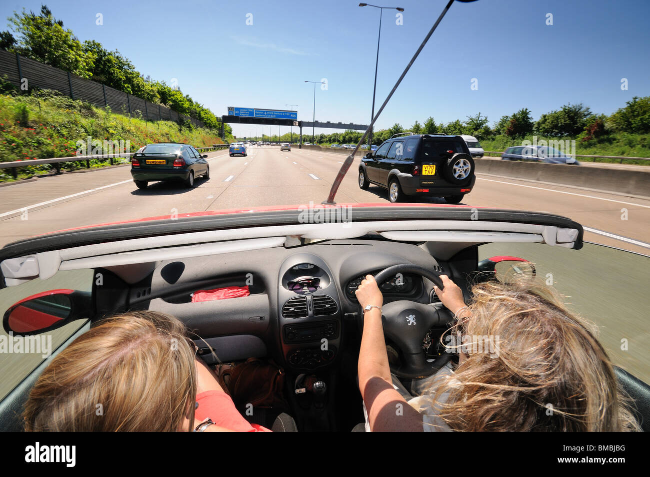 Open top car with female driver and passenger on open road Stock Photo ...