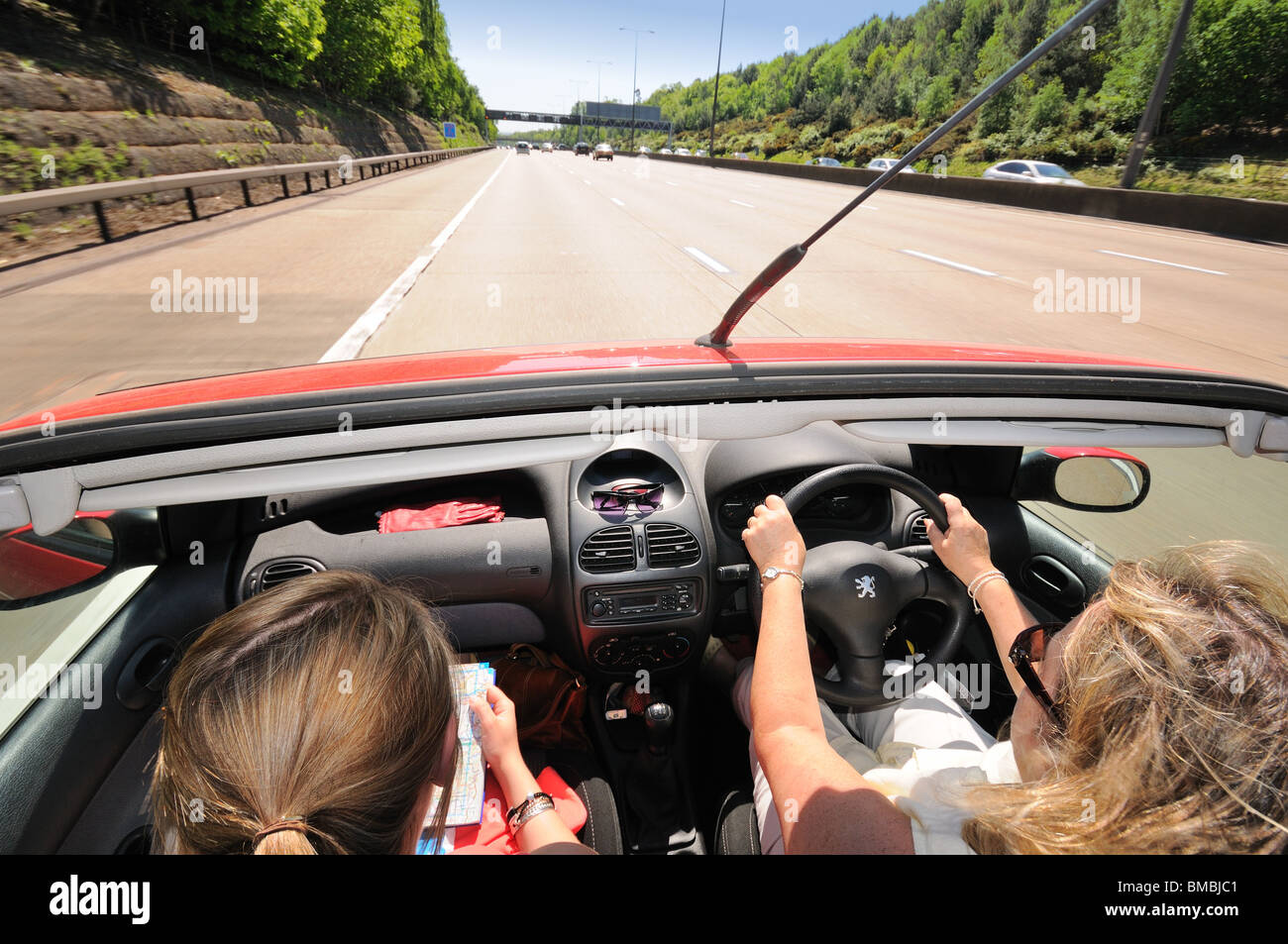 Open top car with female driver and passenger on open road Stock Photo ...