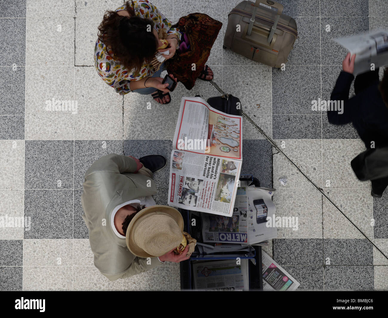 Overhead view of commuters reading the London Metro free newspaper at ...
