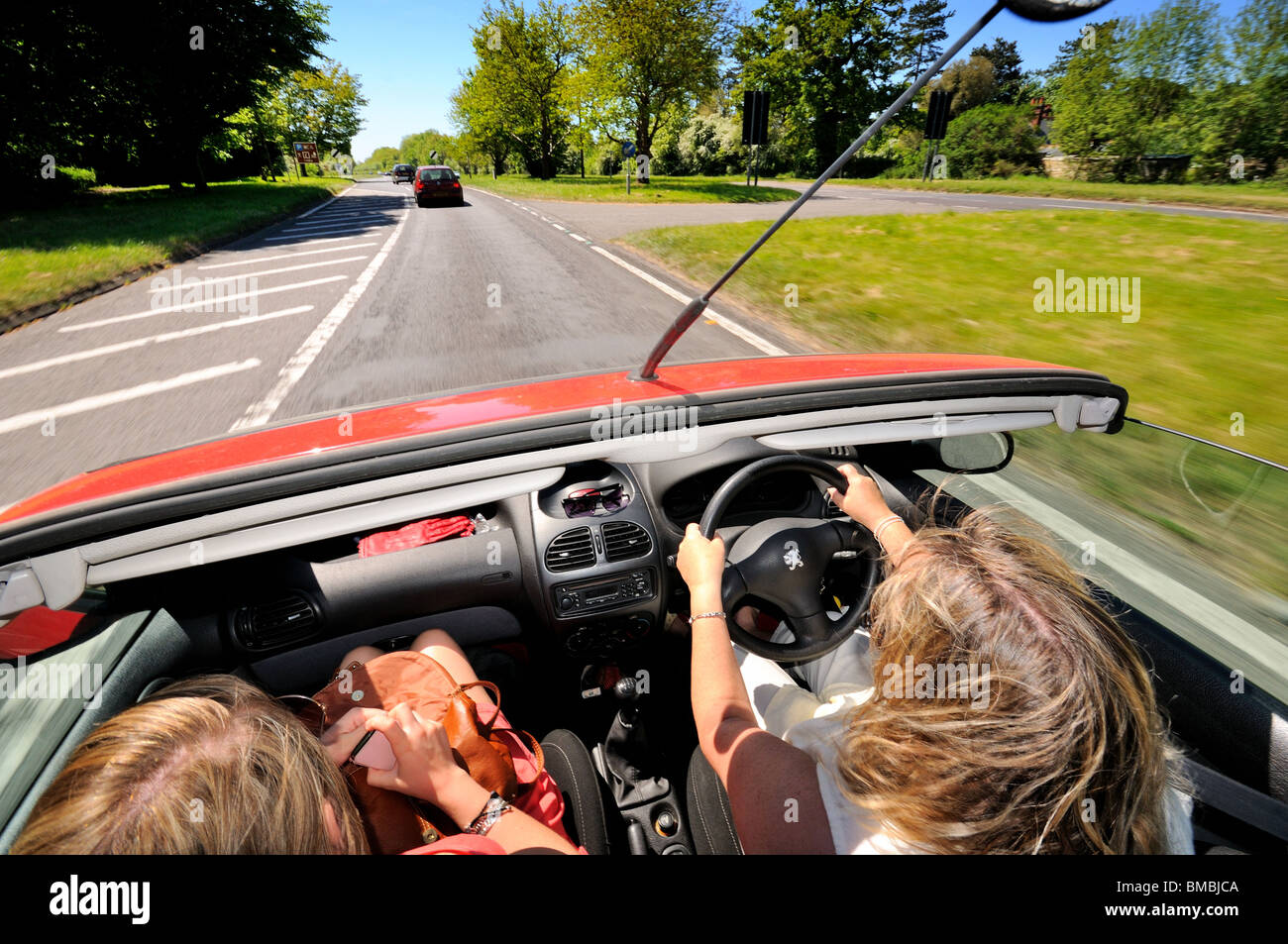 Open top car with female driver and passenger on open road Stock Photo ...