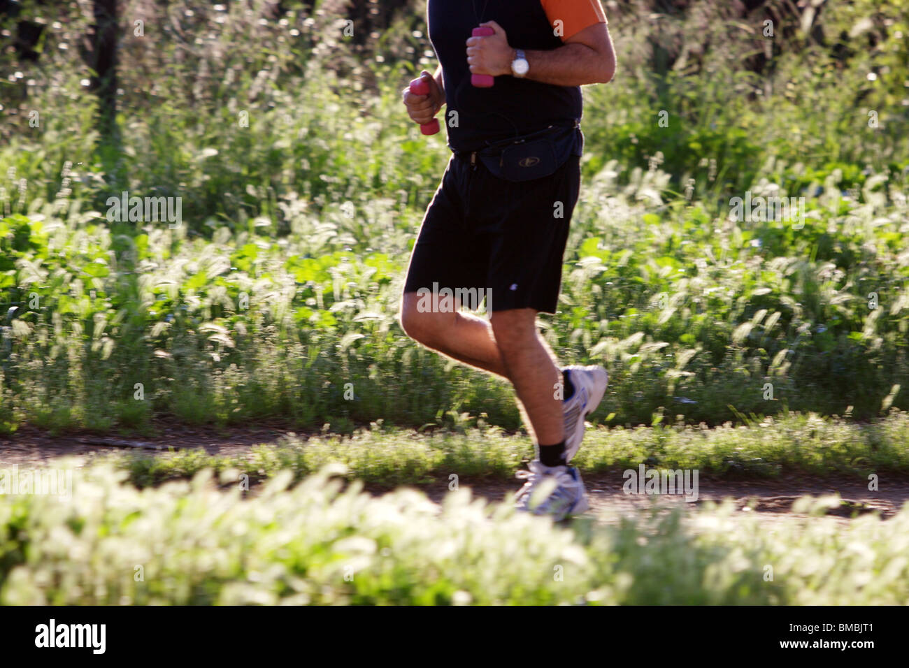 man running outdoor in the park with weights in the hands Stock Photo ...
