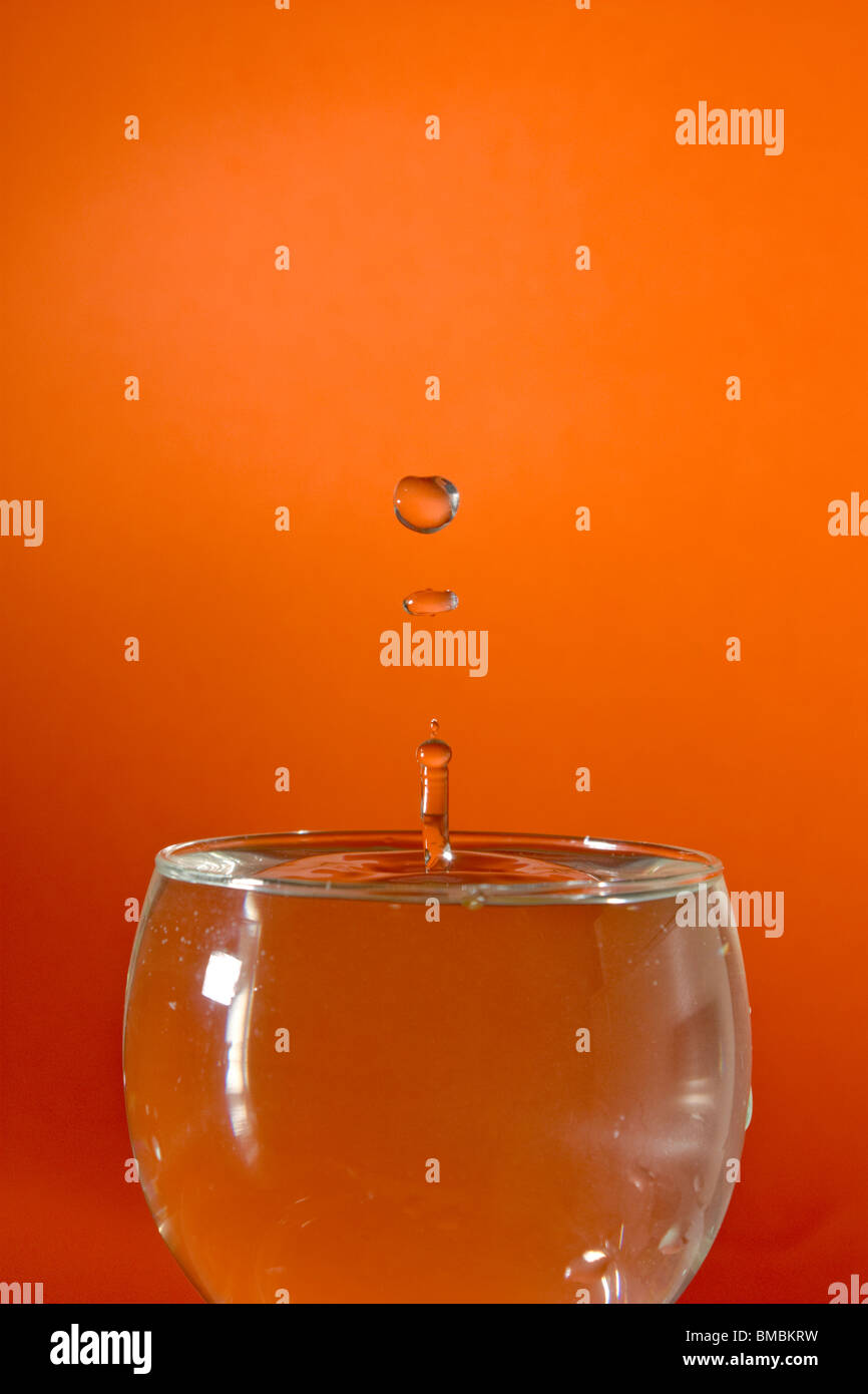 Water drop splashes into a cup full of water Stock Photo - Alamy