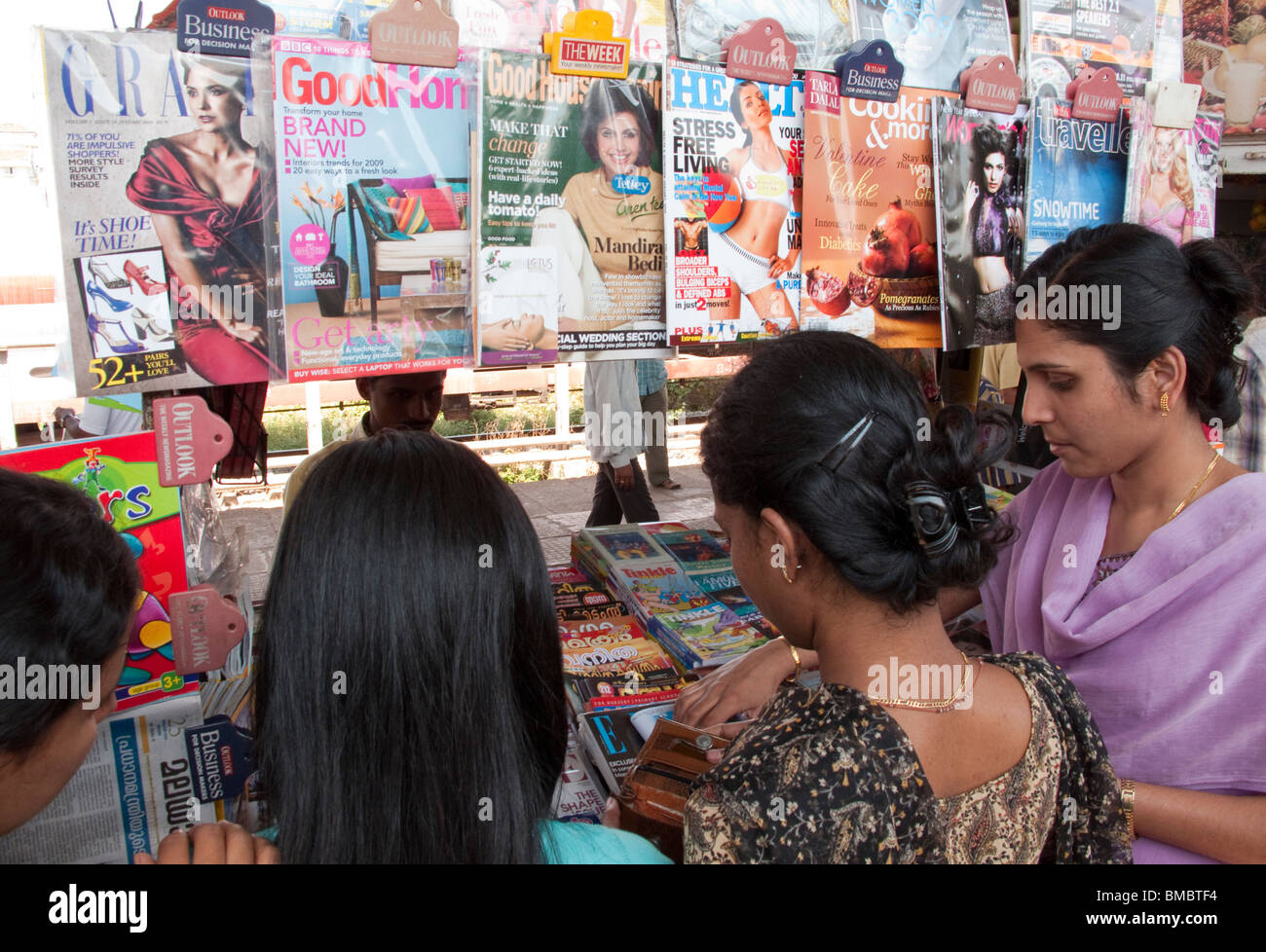 Indian women looking at magazines for sale at a station in India Stock ...