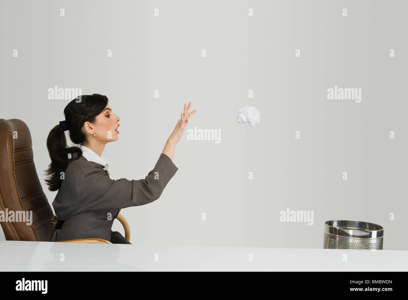 Businesswoman throwing crumpled paper into a wastepaper basket Stock ...