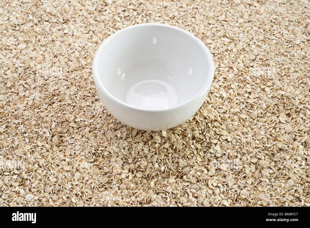 Empty white breakfast dish on a pile of porridge oats Stock Photo - Alamy